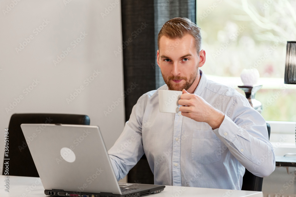 Calm relaxed man sitting down in his living room with a laptop computer ...