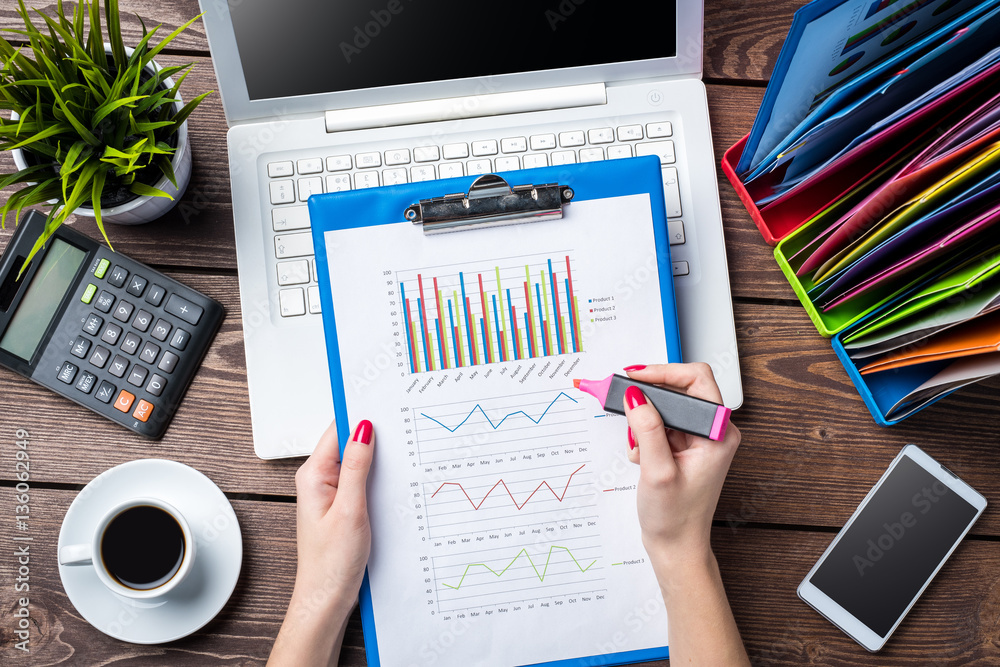 Overhead shot of office desktop with modern computer, graphs and charts ...
