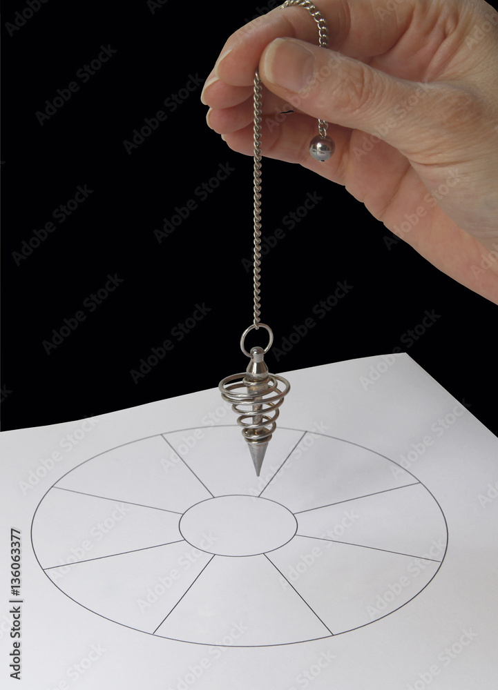 Dowsing with chart - female hand holding a spiral dowsing pendulum over ...