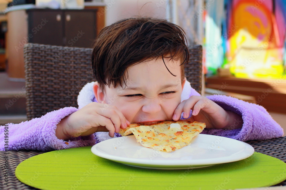 Very hot the last slice of pizza eating boy in a café near the pool ...