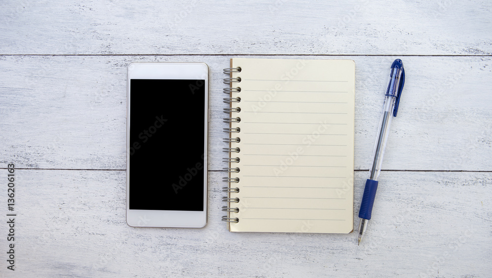 Smartphone and blank notebook on white wood texture background, new ...