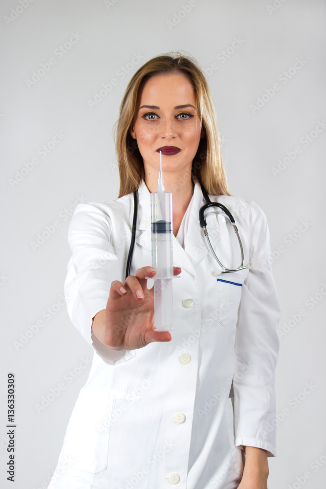 Injection concept. Female doctor with big syringe and stethoscope ...