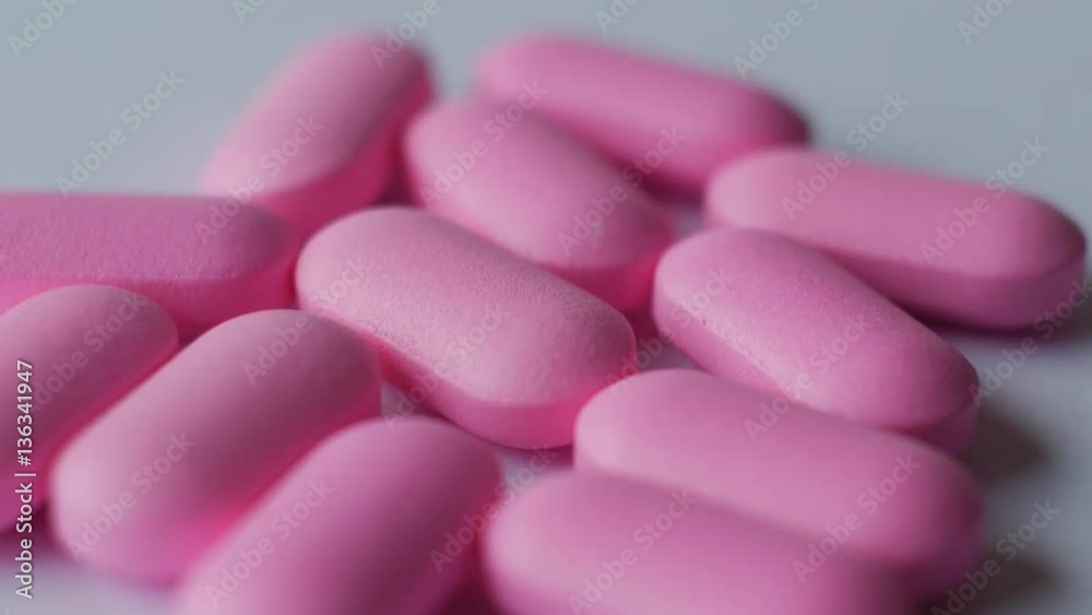 Pink medication pill turning on a table on a white background. Stock ...