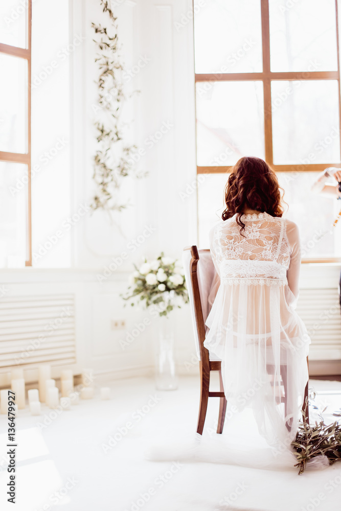 girl in white transparent boudoir gown sitting on a chair with his back ...