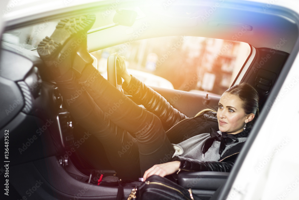 Relaxing in the car. Woman putting her legs on the car dashboard ...