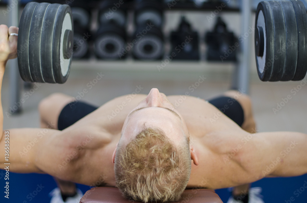 Muscular young man shirtless, lifting dumbbells training pecs on gym ...