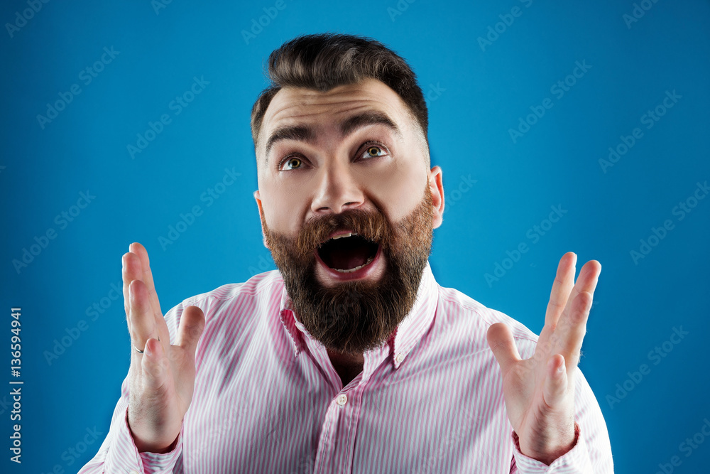 man with a beard in a pink shirt on a blue background shouting ...