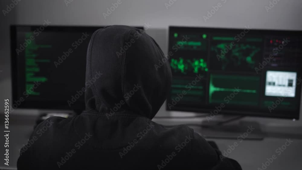 Rear view on the hacker who is engaged clandestine cyber attacks to the ...