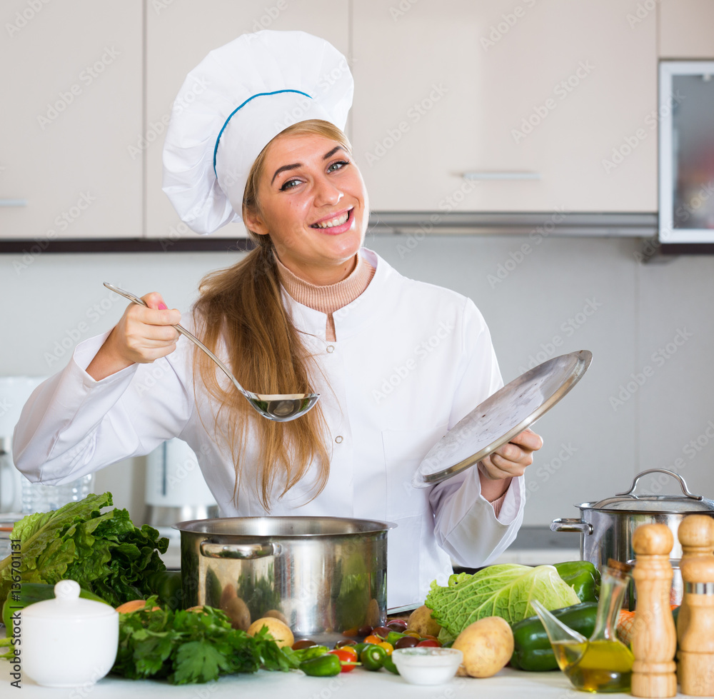 Happy female cook preparing veggies and smiling at home foto de Stock ...