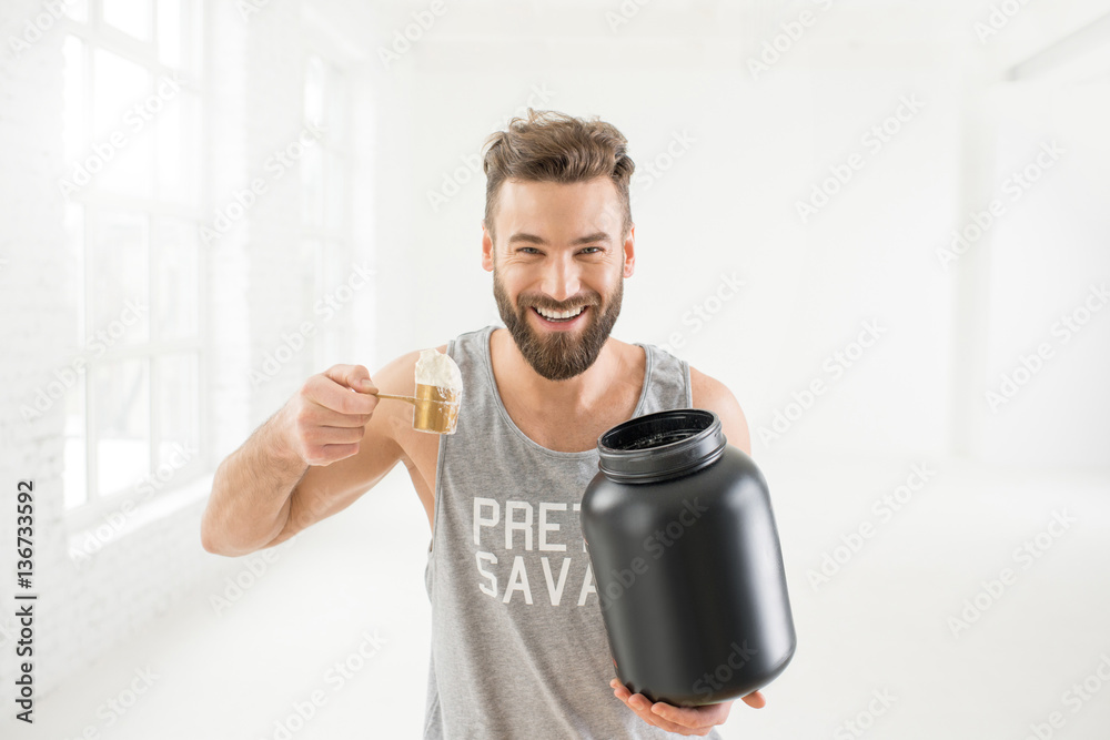 Athletic man in sportswear pouring with scooper protein powder in the ...