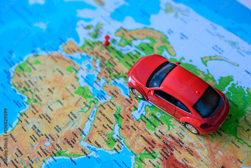 close up on a hand placing a pin on a map and car toy mark where to go ...