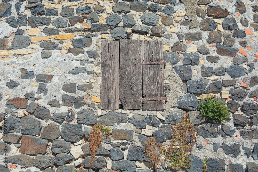 Shuttered window in the wall of basalt in the picturesque village of ...