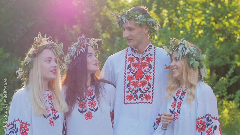 a group of girls and boys in the Slavic national dress in the woods ...