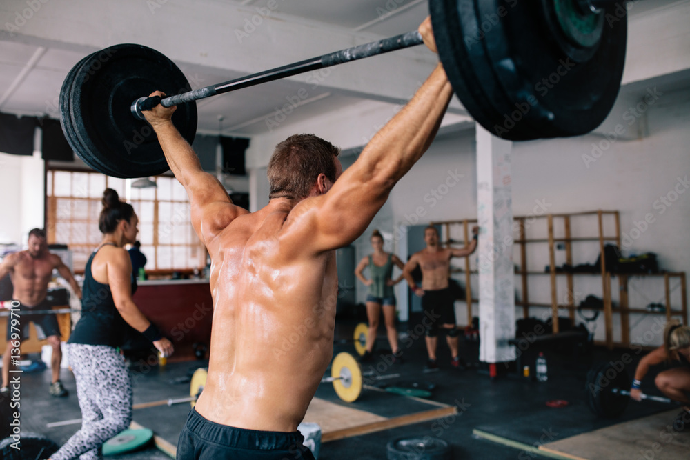 Muscular bodybuilder lifting weights in gym Stock Photo | Adobe Stock
