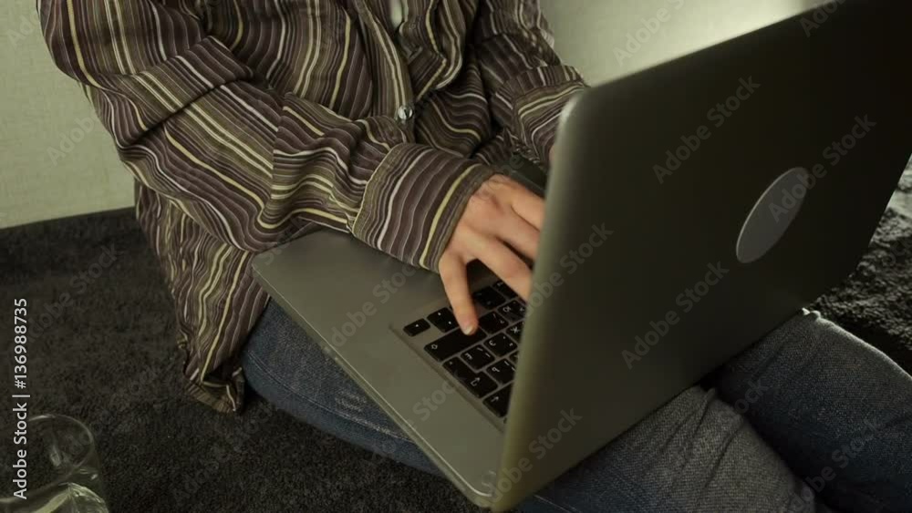 Close up of female hands using laptop sitting down on the floor at home ...