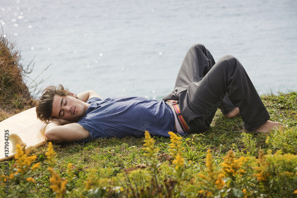 Surfer sleeping on surfboard on bluff Stock Photo | Adobe Stock