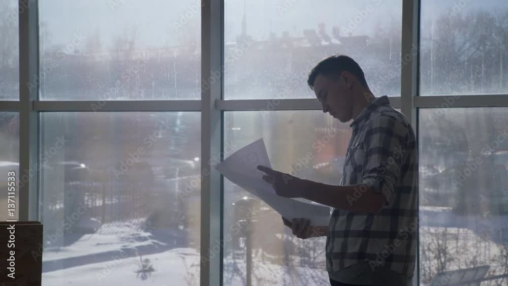 Man at the window looking documents that iterates over in his hands ...