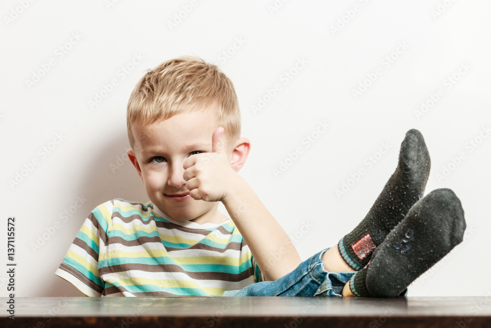 Little boy sit with legs on table and thumbs up. Stock Photo | Adobe Stock