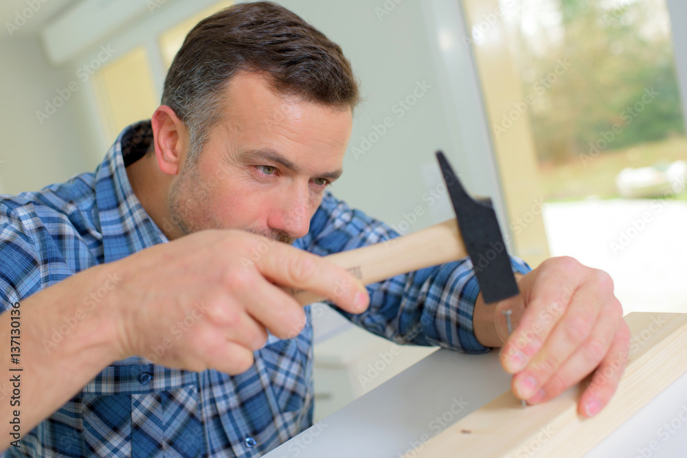 Man tapping nail into wood Stock Photo | Adobe Stock