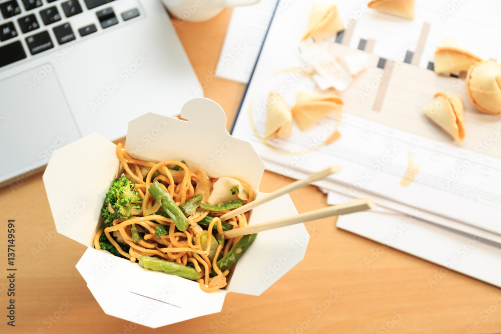 Chinese food box on the office desk. Eating at the office. Overtime ...