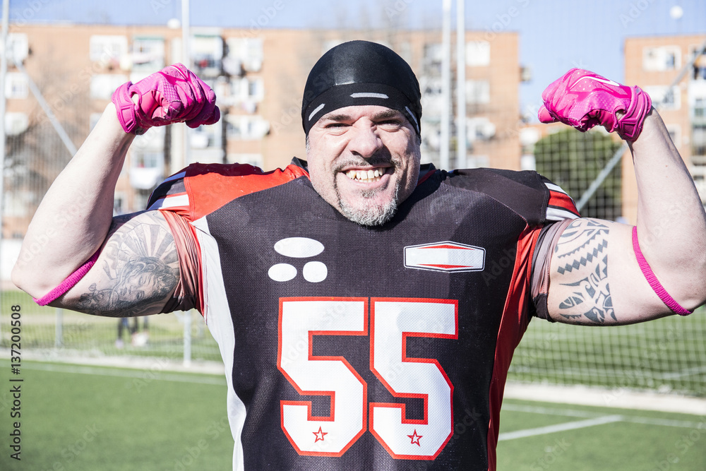Portrait of confident American football player flexing his muscles ...