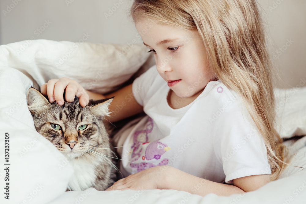Charming little girl hugging her cat lying Stock Photo | Adobe Stock