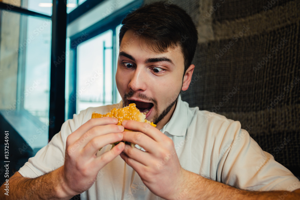 oung man enjoys eating fast food burger delicious Stock Photo | Adobe Stock