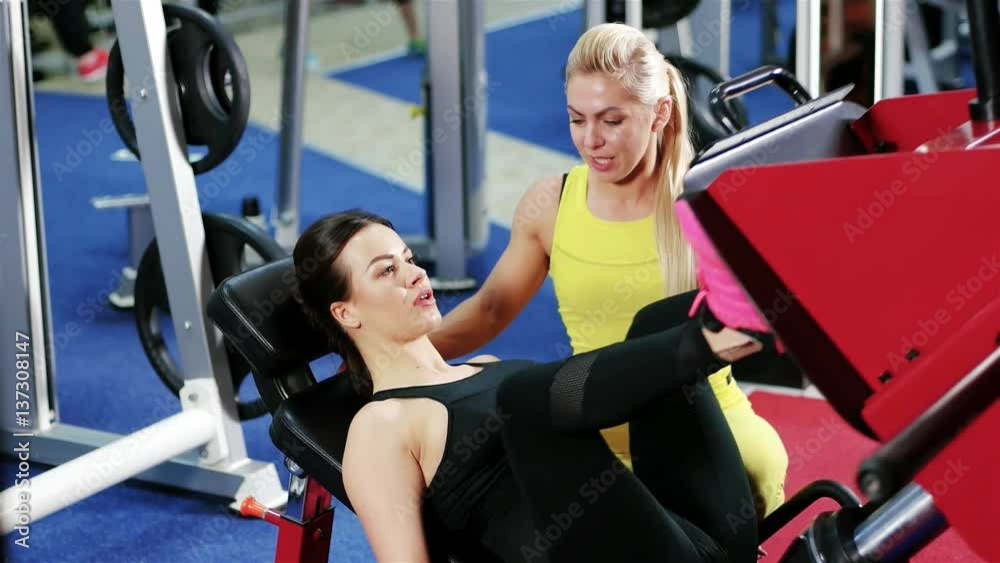 Girl is engaged in fitness with the coach in the gym, the trainer helps ...