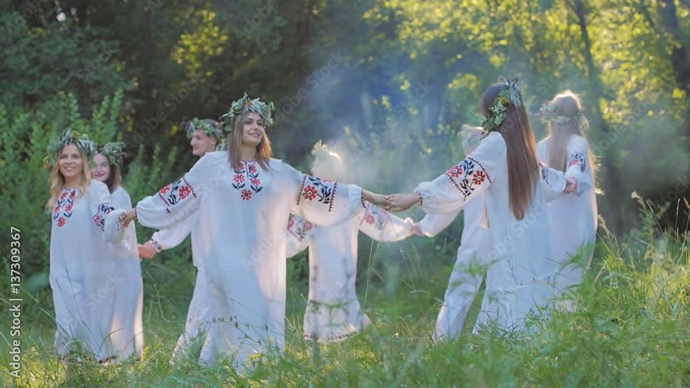 a group of young people in national Slavic costumes dance in a circle ...