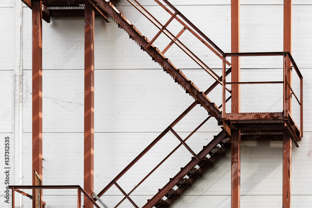 Old rusty metal ladder against a white wall background. Metal steps ...