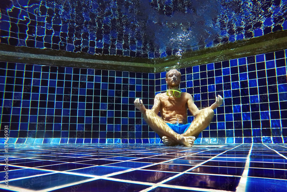Man underwater portrait in yoga position inside a swimming pool in the ...