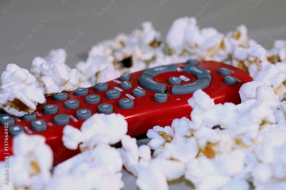 Delicious popcorn is scattered around a television remote control - a ...