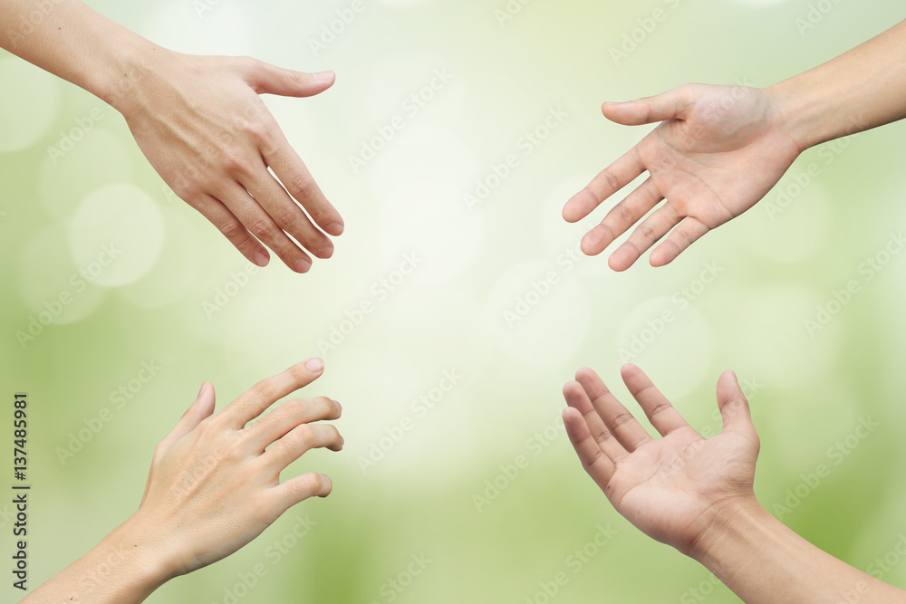 four human hands try to reaching on blur natural green color background ...