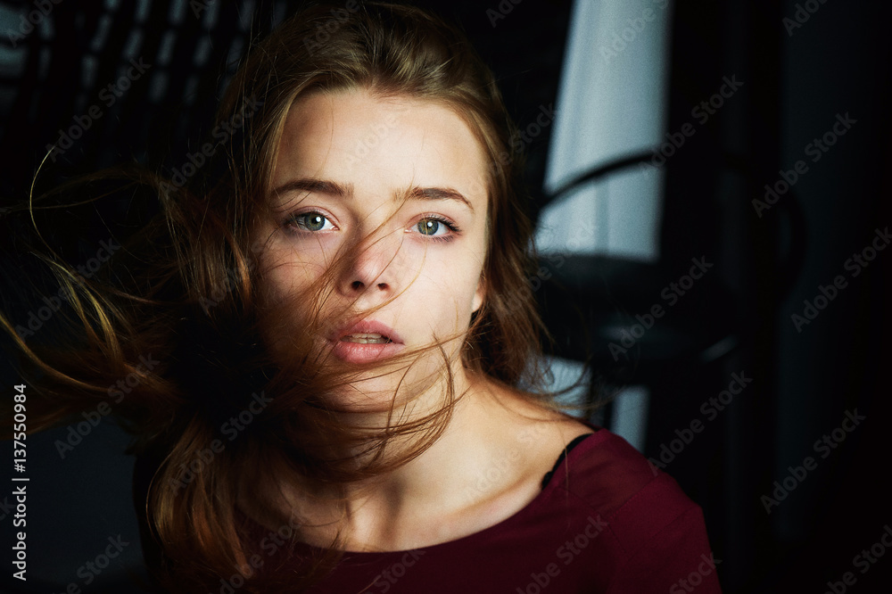 Beautiful girl looks piercing eyes into the camera. Hair flying. Drama. Studio photography in ...