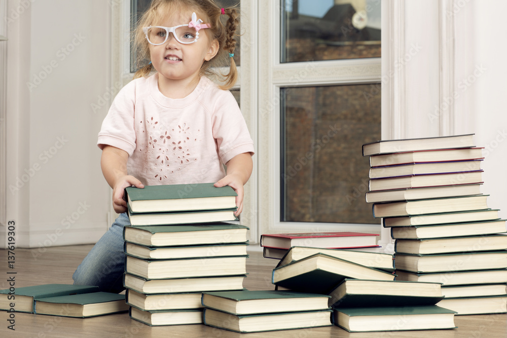 Little girl sits on the floor and play. Portrait of child has pile of ...