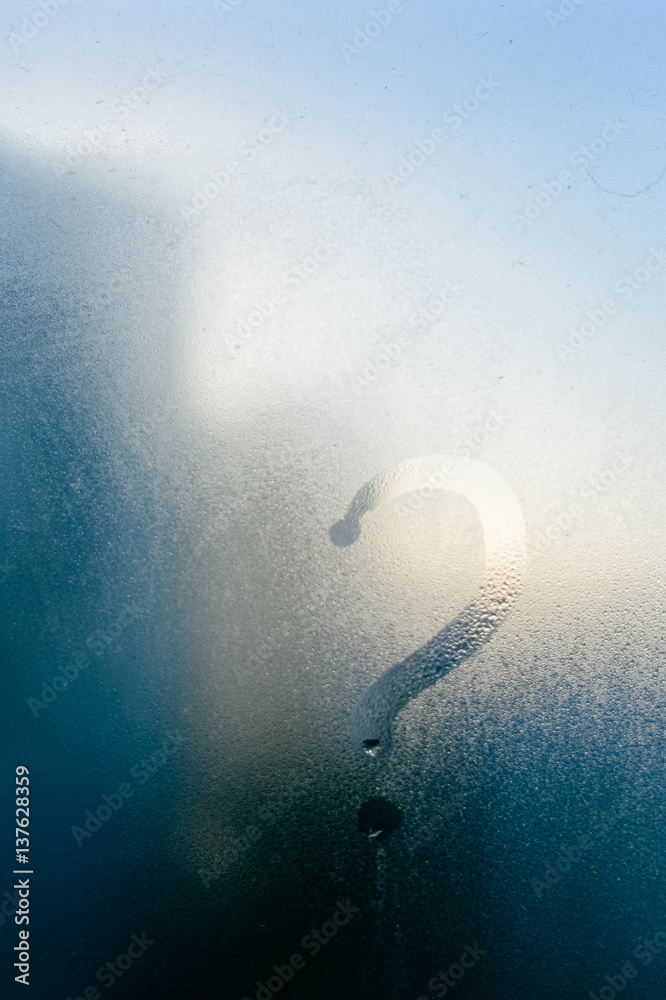 Question mark symbol on sunny foggy window glass blurry condensation ...