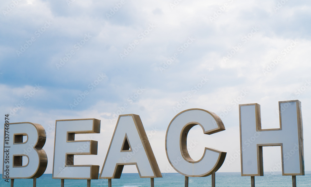 Big white and gold "Beach" sign over blue sea and sky background Stock ...