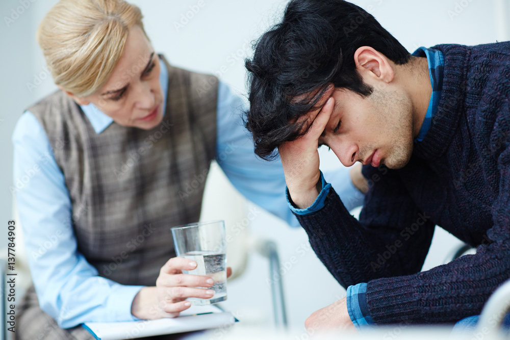 Tense man touching his head with psychologist near by Stock-Foto ...