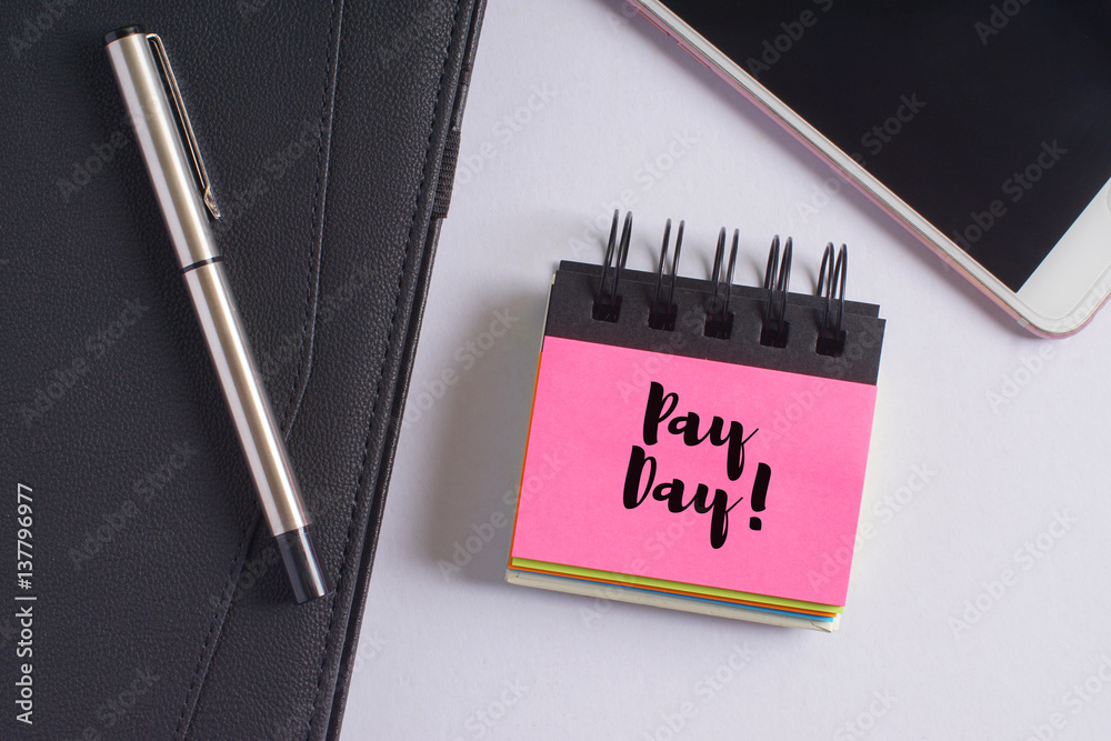 "Pay day" words on pink sticky notes with fountain pen, diary and ...