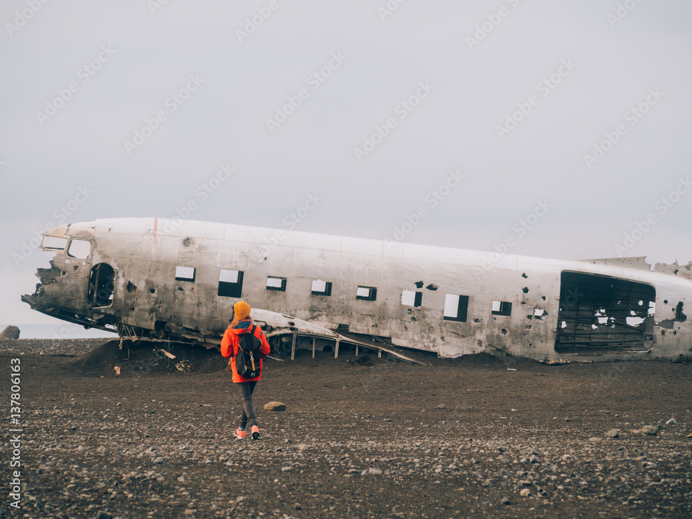 Woman walking alone against old plane wreckage Stock Photo | Adobe Stock
