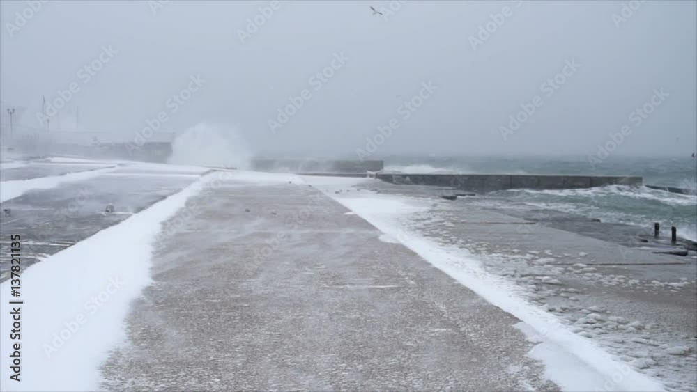 Snow covers the concrete coast with huge wave on the background Stock ...
