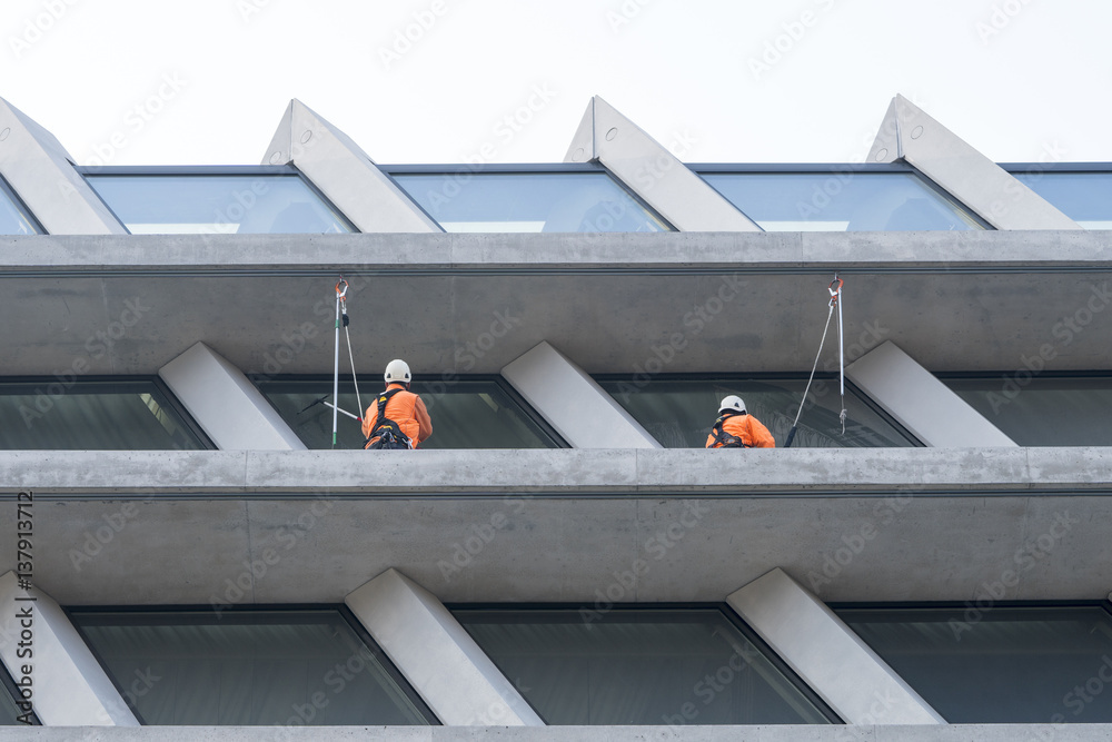 Window washers cleaning the glass facade of a modern building, high ...