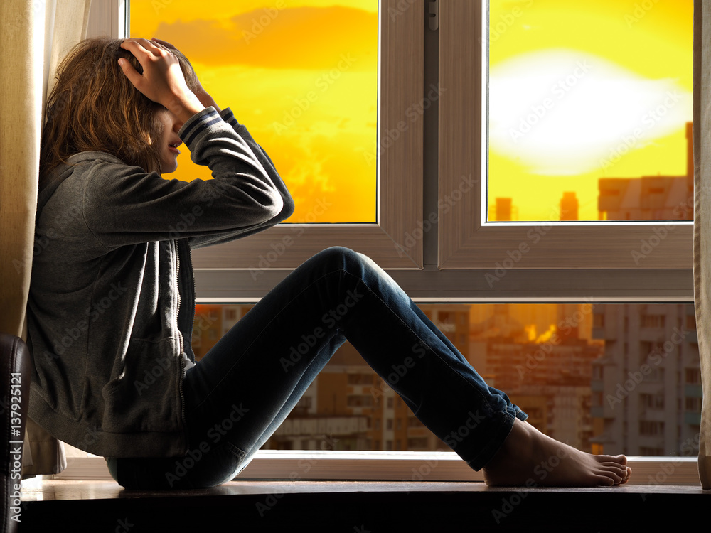 The teenager sitting on the window holding his head. The girl in jeans ...