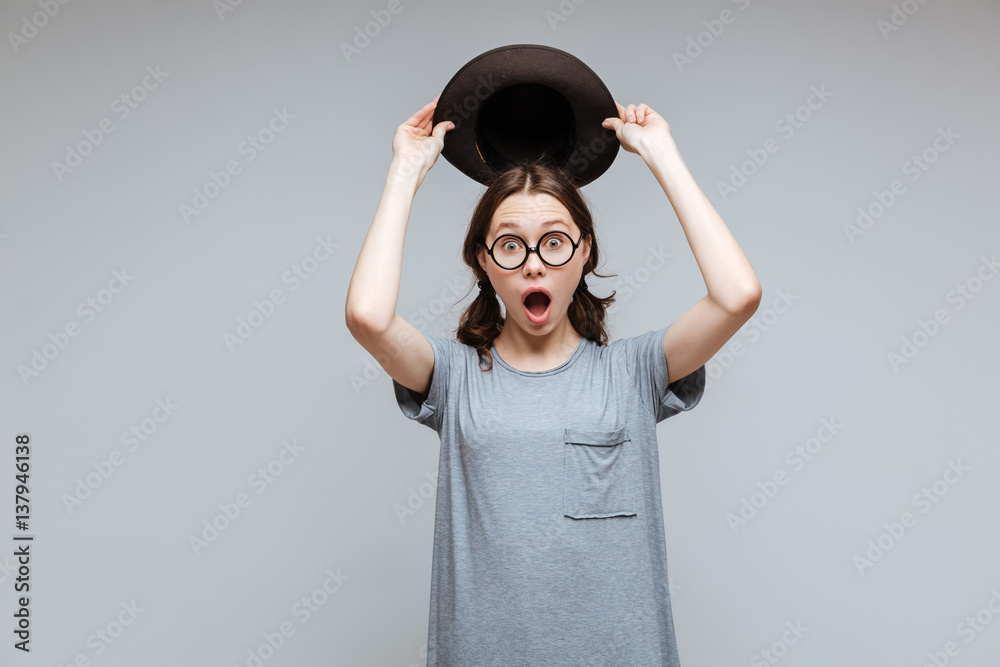 Shocked Female nerd holding overhead her hat Stock Photo | Adobe Stock