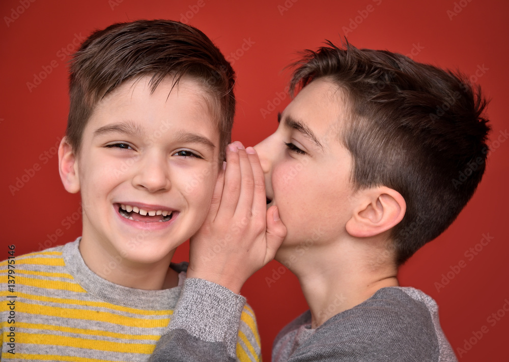 Young boy whispering secret into ears of smiling brother foto de Stock ...