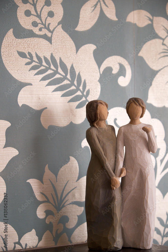 Foto de wooden statue of two women holding hands, statue is on a black ...