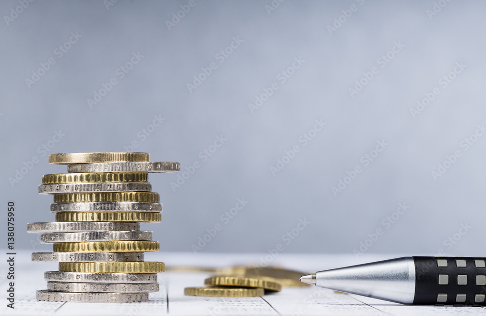 Ein Stapel Euromünzen und ein Stift auf einer Tabelle, Hintergrund ...