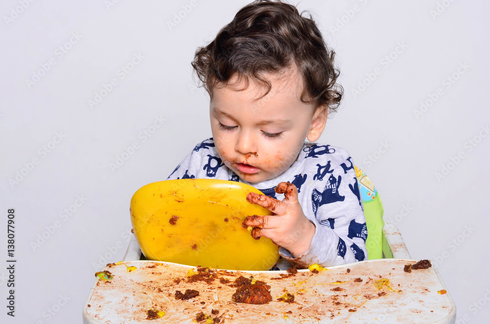 Fotka „One year old kid eating a slice of birthday smash cake by ...