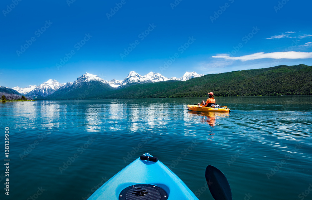 Kayaking in the spring by snow covered mountains on Lake McDonald in ...