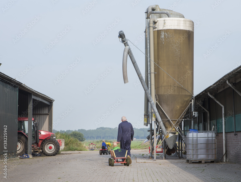 Granddad farmer at the farm with children. Farmyard. Silo. Tractor ...